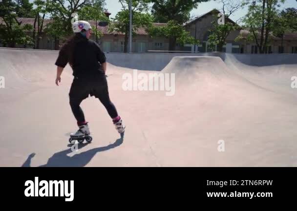 young skilled woman rollerblading and jumping on the ramp in the skate ...