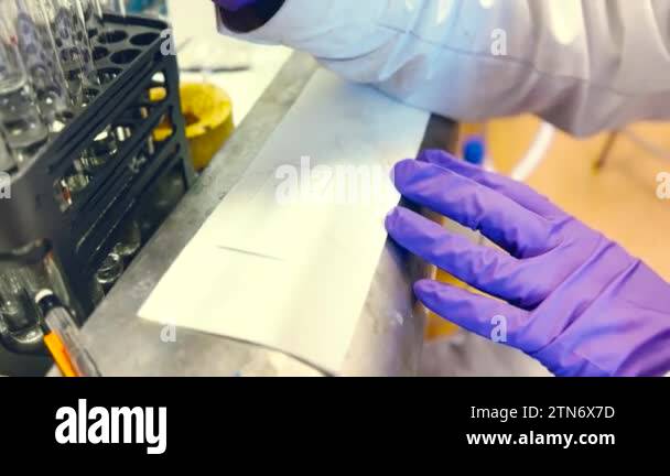 A woman scientist checking thin layer chromatography on a silica plate ...