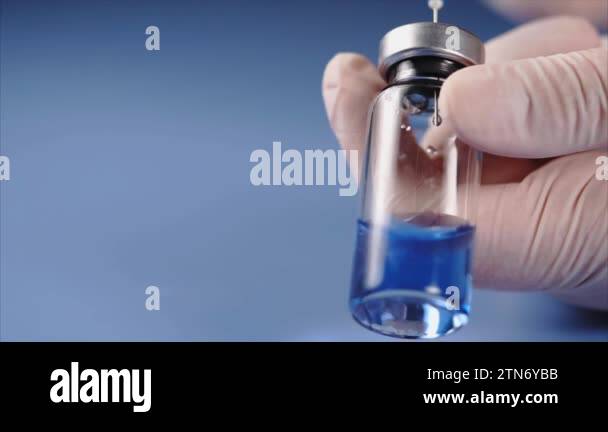 Close up mixing of medicine. Doctor using syringe to squirt fluid into ...