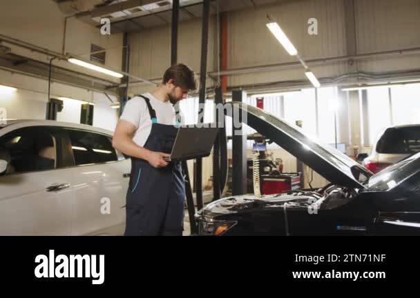 Engineer with laptop makes computer diagnostics of the car engine in ...