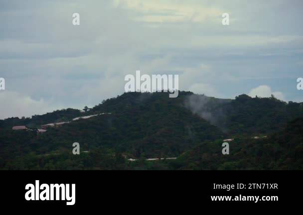 Cloud floating over a village and mountain. Misty fog blowing over tree ...