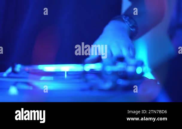 DJ mixes tracks on DJ console lit color music in nightclub party. Dj ...