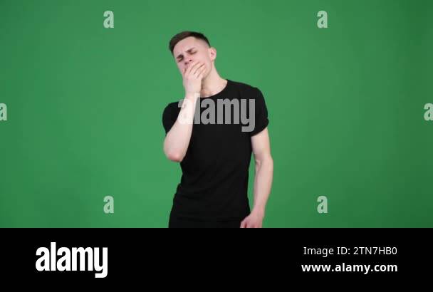 Sleepy Caucasian man is captured on a green screen background. He is ...