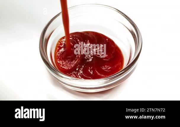 Ketchup is poured into a bowl. Ketchup Bowl on a Table with white ...