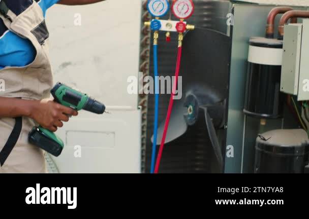 Qualified electrician starting work on busted air conditioner, using ...