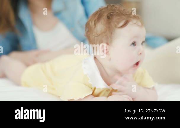 baby girl lies on her stomach on the bed, Mom kisses her daughter Stock Video Footage - Alamy
