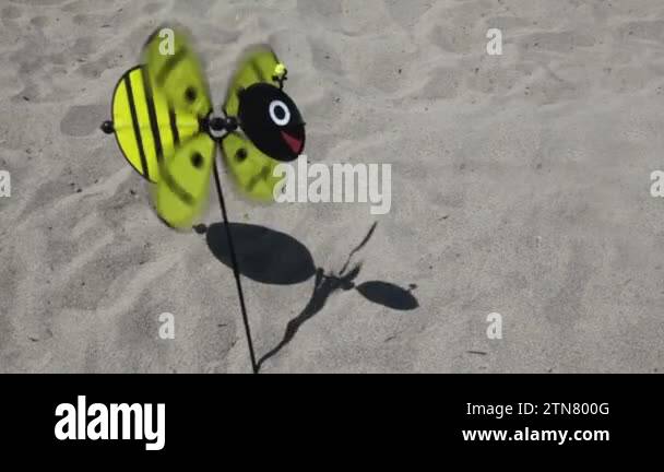 Toy in the shape of a bee with a rotating propeller stuck in the ground ...