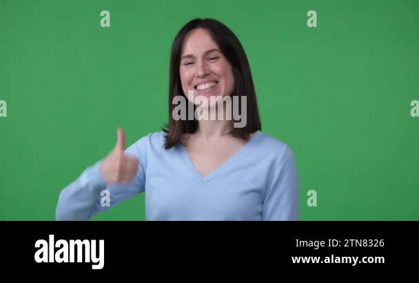 A cheerful Caucasian woman standing on a green screen background ...