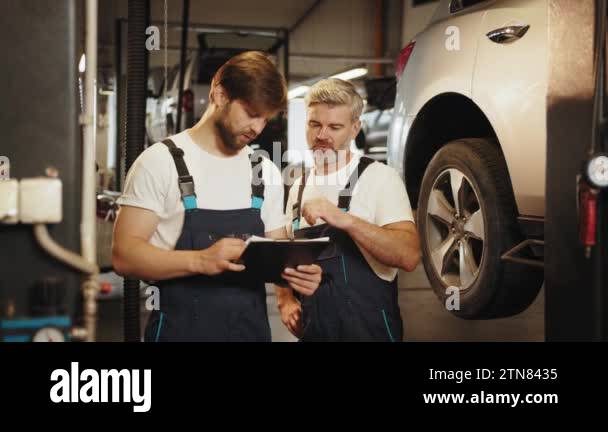 Mechanic man shows report on a tablet to the caucasian coworker at ...