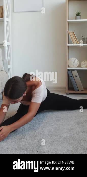 Vertical video. Split exercise. Home stretching. Young flexible fit ...