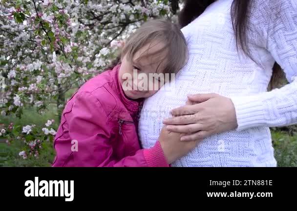 Young girl smiling hugs belly of pregnant mother. Pregnant mother ...
