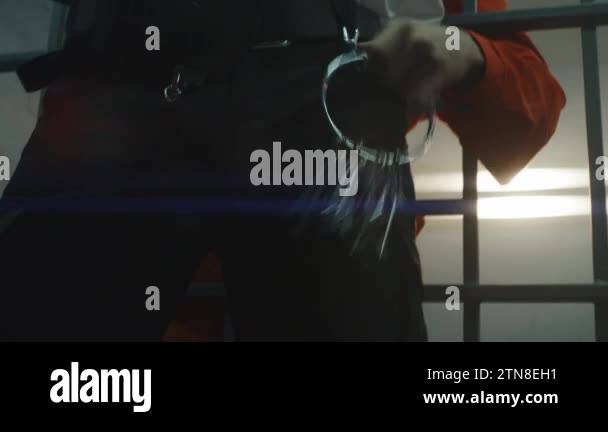 Cinematic shot of male prisoner strangling prison officer, taking keys, opening prison cell ...