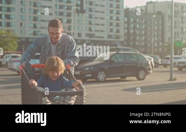Portrait of happy dad with son. Father rotates grocery cart with son ...