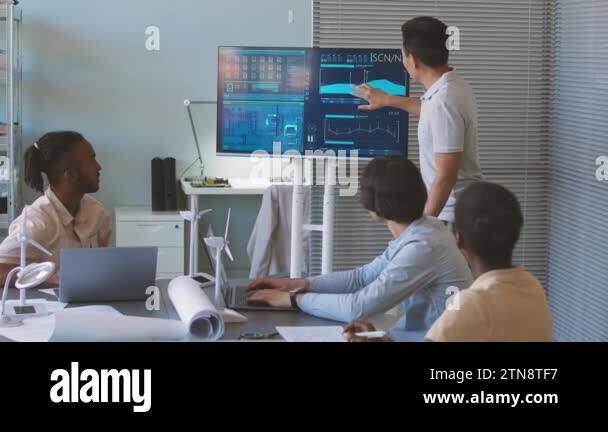 Young Asian male engineer showing charts on projector screen and ...