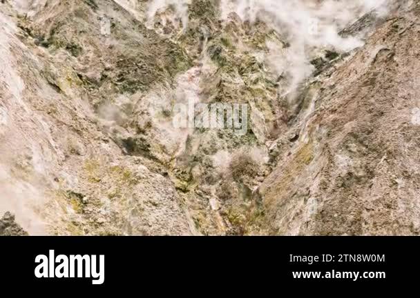 Aerial drone of volcanic activity on a mountainside with smoke and ...