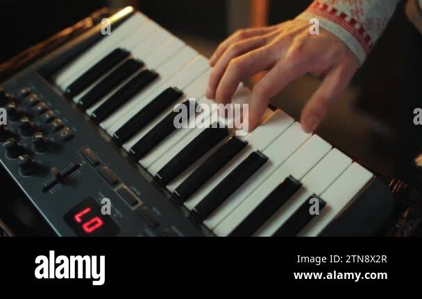 Man in kosovorotka shirt hand fast tapping on keys of midi controller ...