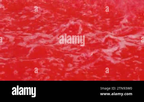 Bloody red color water splashing in slow motion on a rippled surface ...