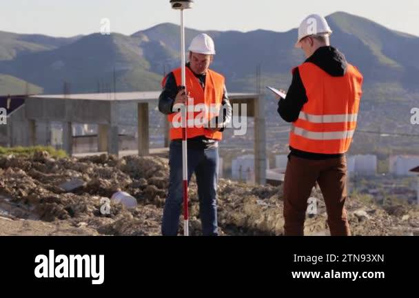 Two surveyors performing geodesic measurements on the top of the ...