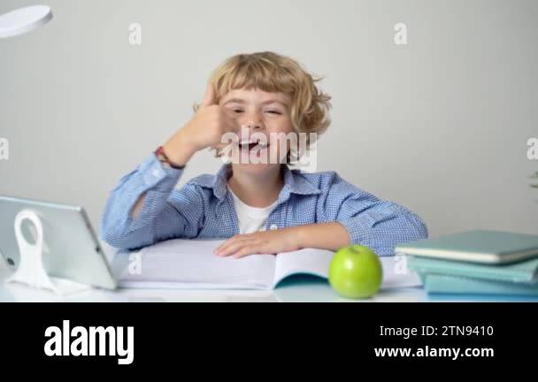 Elementary school student boy or girl writing letters, studying at desk ...