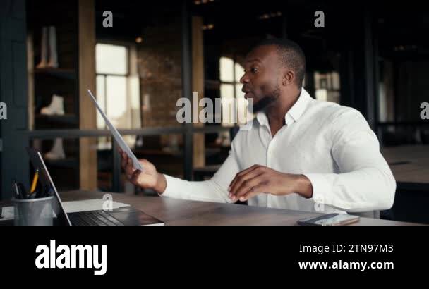 A Black man in a white shirt is brought a report on the work done in ...