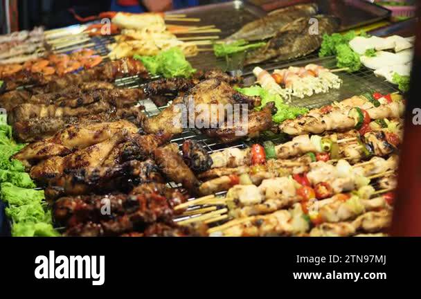 Traditional Asian meat satay street food cooking outdoor at night ...