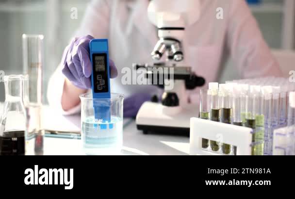 Laboratory scientist in rubber gloves measures pH level of transparent ...