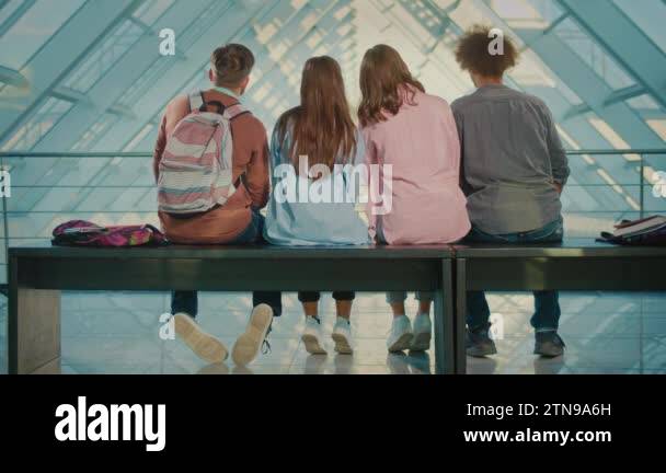 Back view of Students Sitting on Bench in the University HallWay During ...