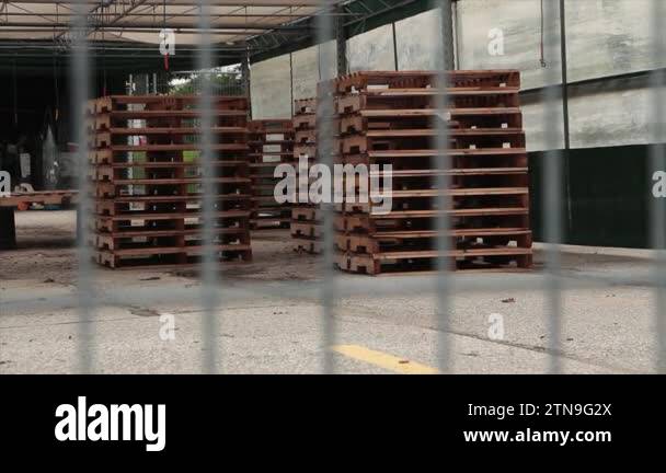piles of wood palettes skids on pavement in outdoor canopy tent ...