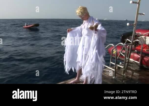 Model in costume of angel clothes pointe shoes on ship near water in ...