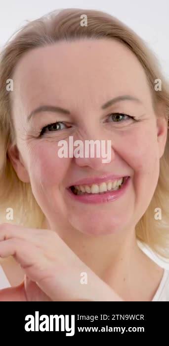 woman sincerely smiles with hands shows a heart squinting her eyes on a ...