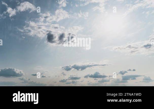 White fluffy clouds slowly float through the blue daytime sky timelapse ...