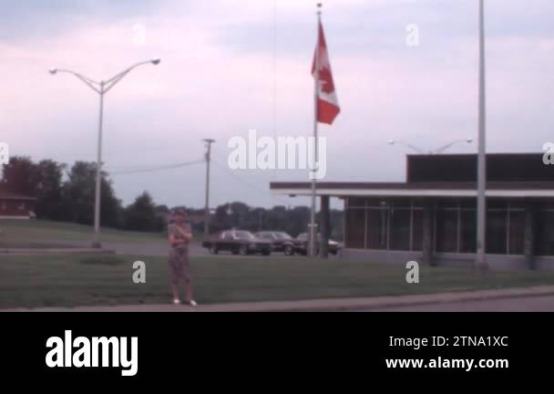1970s footage of Canadian flag waving in wind outside small building ...