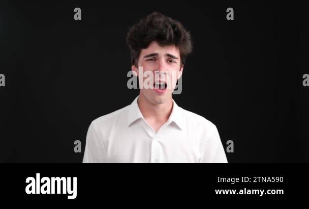 Weary Caucasian man yawning against a black background. His face ...