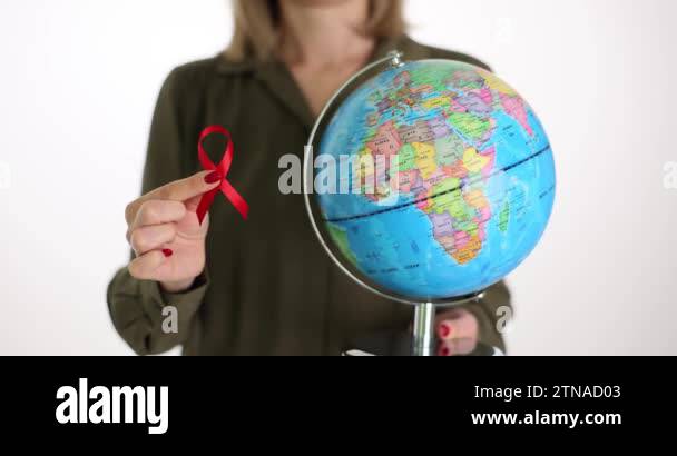 Lady holds red ribbon and big model of Earth in hands standing on white ...