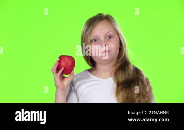 Little girl bites an apple and shows a thumbs up. Green screen. Slow ...