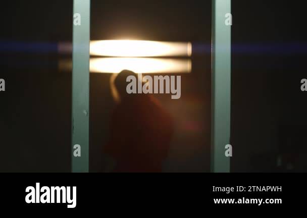 Female prisoner in orange uniform stands near barred window in prison ...