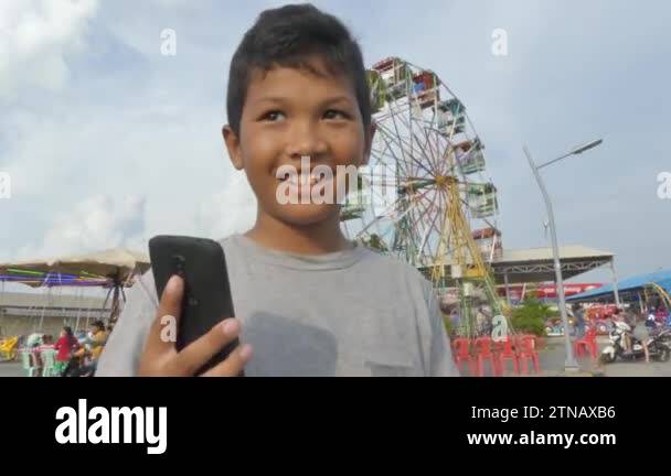 Multicultural Asian boy calls his family on a smartphone while standing ...