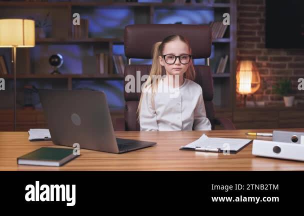 Positive little girl pulling out alarm clock from under table, pointing ...