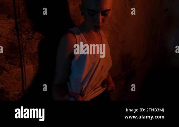 A woman with no hair on her head in a neon-lit basement is drawn behind ...