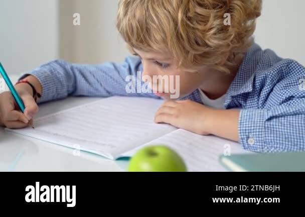 Elementary school student boy or girl writing letters, studying at desk ...