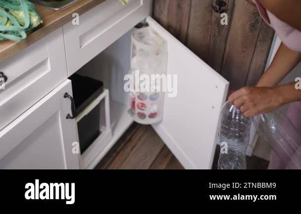 Separate garbage collection at home, a woman puts plastic bottles in ...