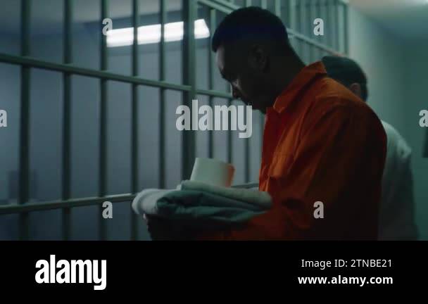 Warden brings guilty prisoner in jail cell and takes off handcuffs ...