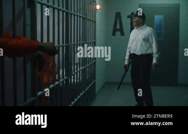 Warden with baton and bunch of keys comes to jail cells and talks with ...