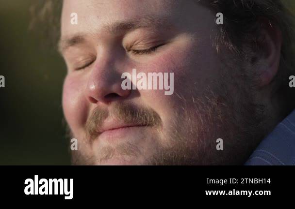Young man closing eyes in meditation close up face sitting at park ...