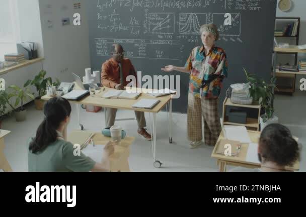 Tilt down shot of female student with prosthetic arm pointing at graphs ...
