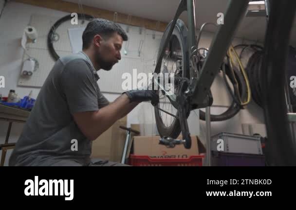 Man bicycle mechanic installs cycle chain on bike. Technician fixes bicycle chain gear at ...