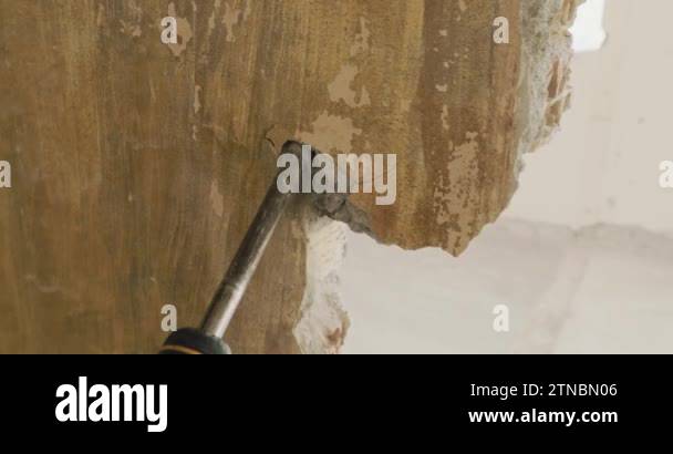 Dismantling the walls in the premises, the builder removes the plaster ...