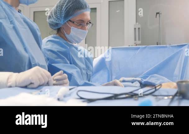 A phlebologist surgeon and assistant performs an operation on legs with ...