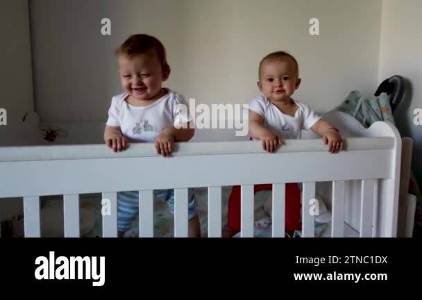 Two fraternal twins sisters laughing, dancing and having fun in crib Stock Video Footage - Alamy