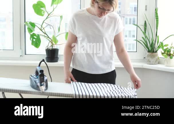 Woman ironing children striped dress on ironing board. Hot stem from ...